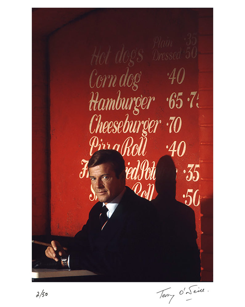 Roger Moore as James Bond smoking a cigar in a diner on the film set of ...